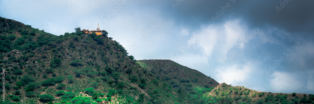 hindu temple on a hill covered in vegetation with the tower and spire ...
