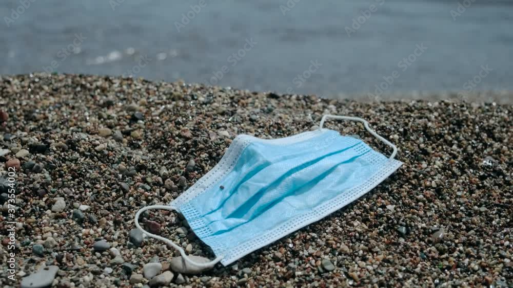 Vidéo Stock Close-up of used disposable face mask on the sandy pebble ...