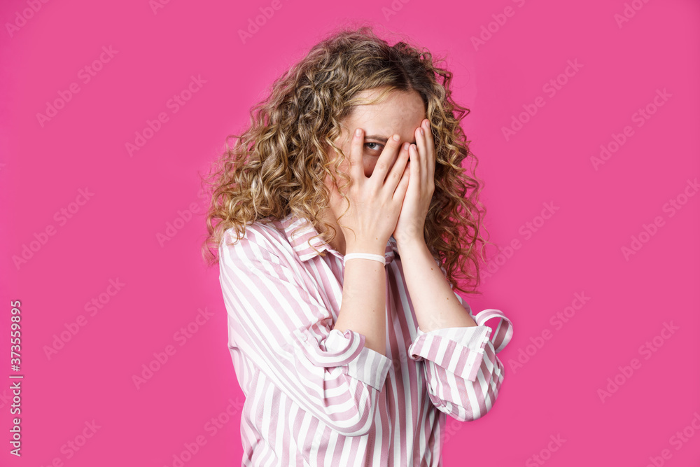 Portrait of shy, timid or ashamed pretty girl covering face and peeping ...