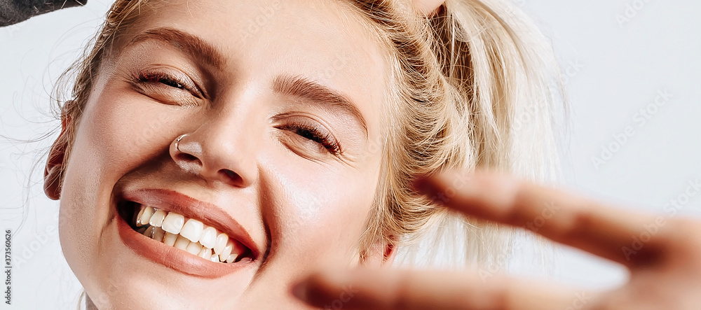 A beautiful blonde girl holds her hair and makes her own hairstyle with ...