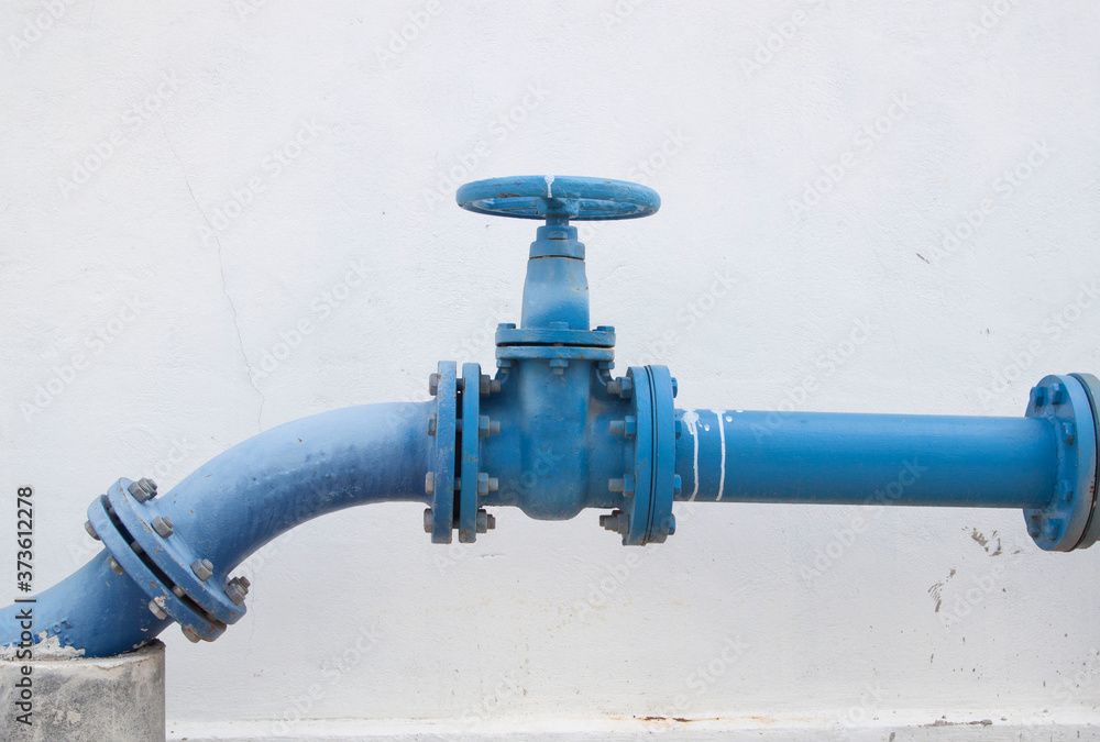 Large water supply valve with a white background of the cement wall ...