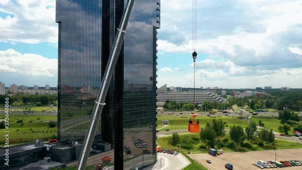 Two construction workers in the building cradle of a mobile crane ...