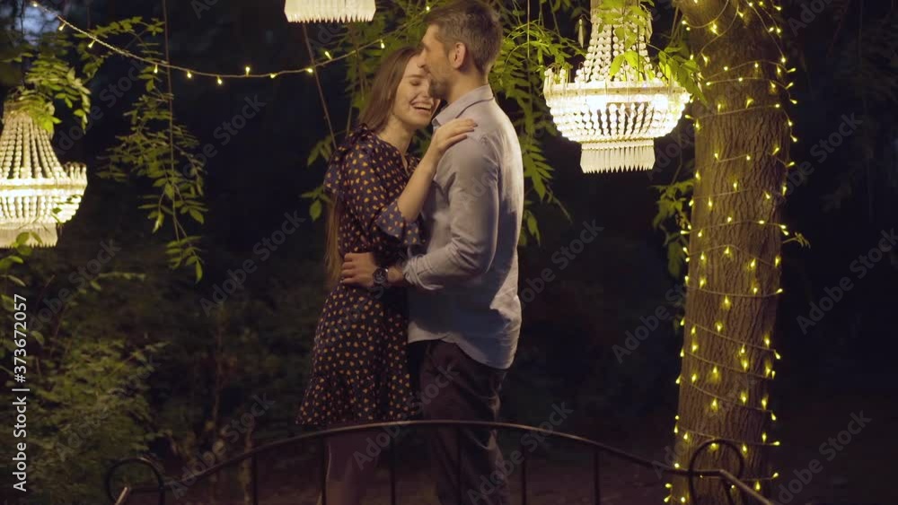 Laughing loving couple hugging in romantic pavilion at night. Portrait ...