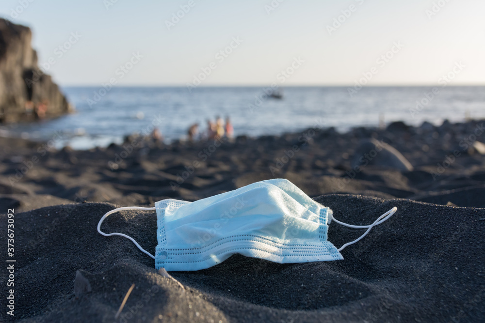 Disposable face mask lying on the beach. Plastic pollution caused by ...