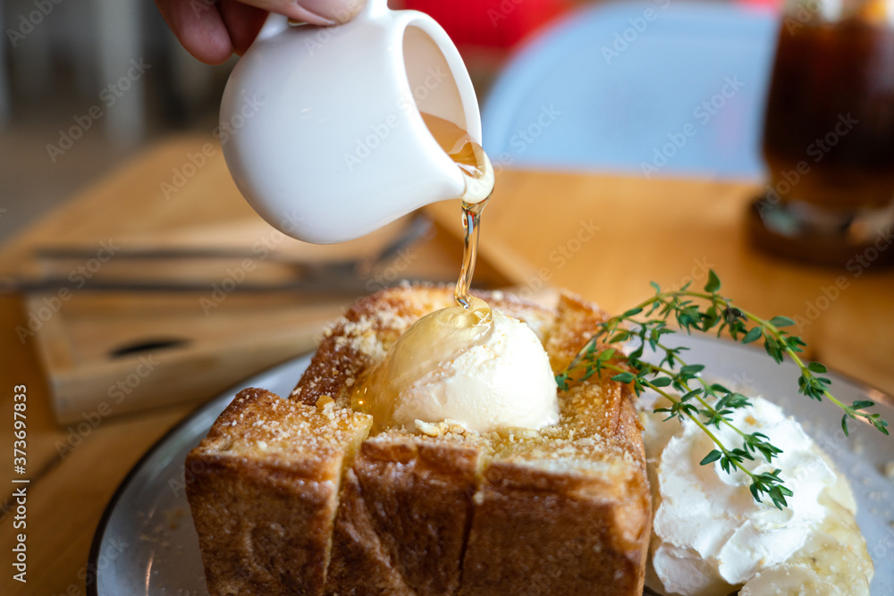 Action of people hand is topping honey sweet on the vanilla ice cream ...