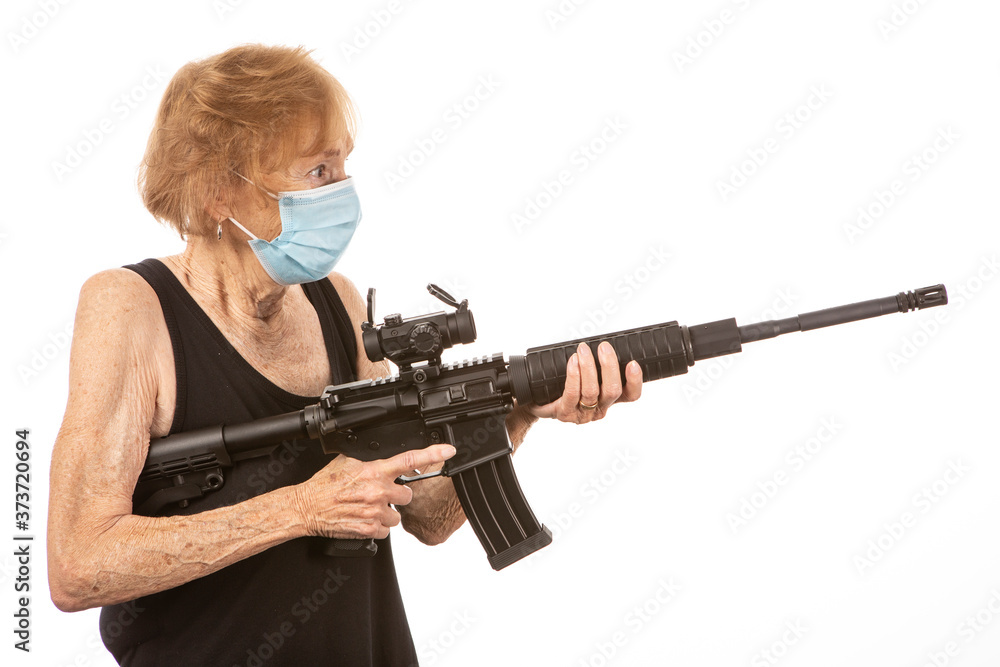 Adult woman with a rifle wearing a mask and aiming off camera on a ...