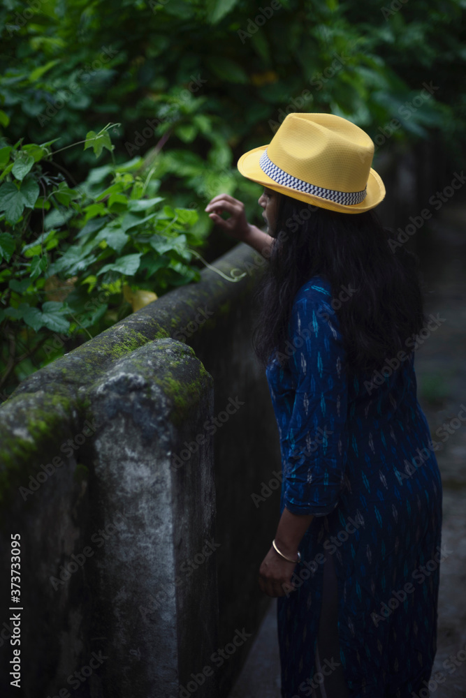 Backside view of an Indian woman standing on garden fencing wearing a ...