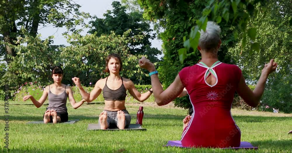 Female yoga master conducts muscle stretching exercises for a group of ...