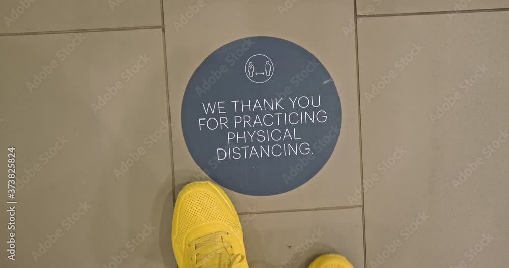 Tourist steps on floor sign at hotel reminding to keep 6 feet social ...