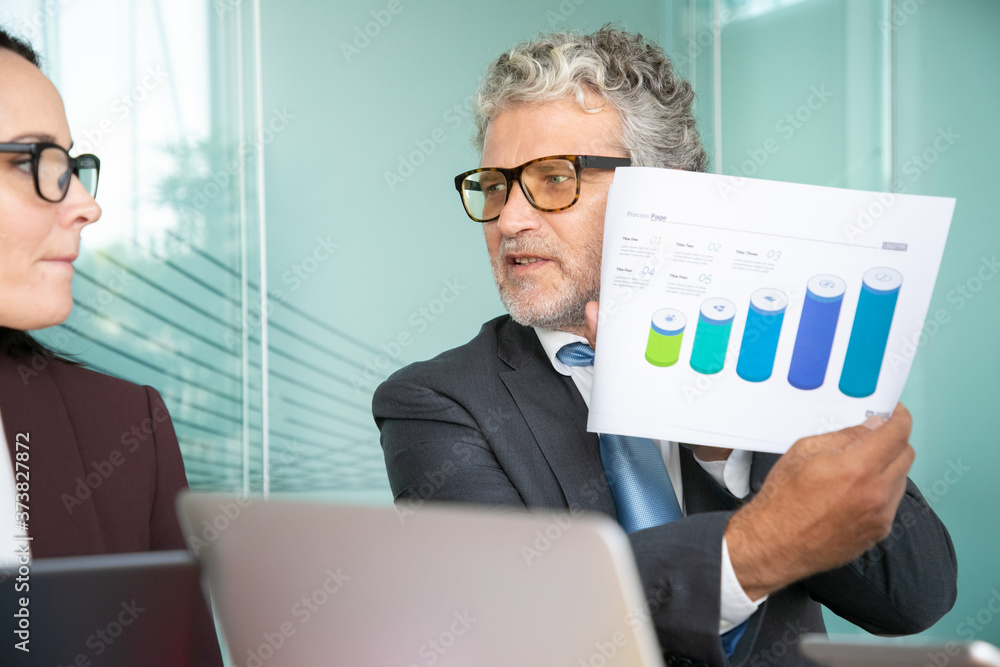 Executive presenting paper report at meeting. Grey haired man in suit ...
