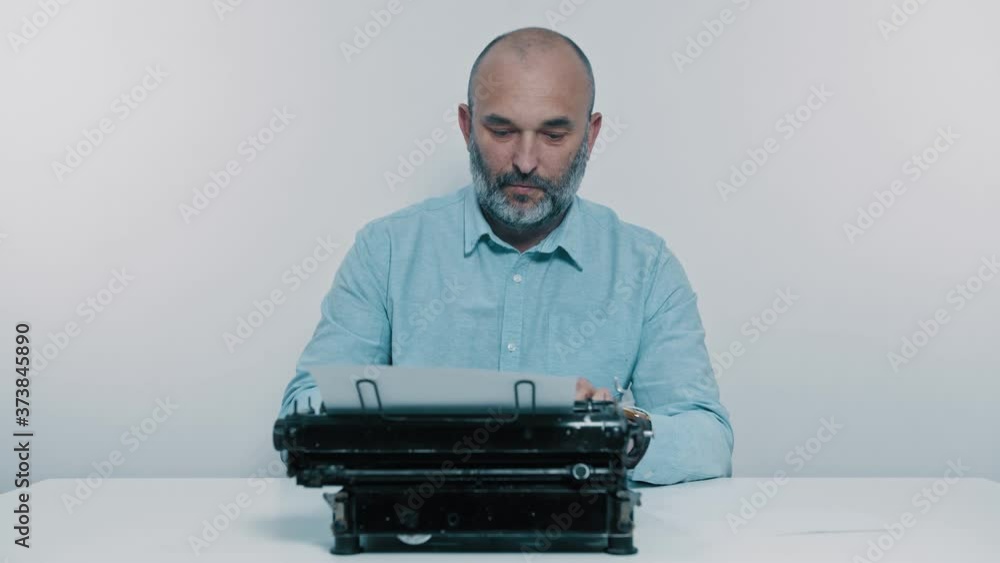 Male writer works sitting at the table. A man writes on paper ...