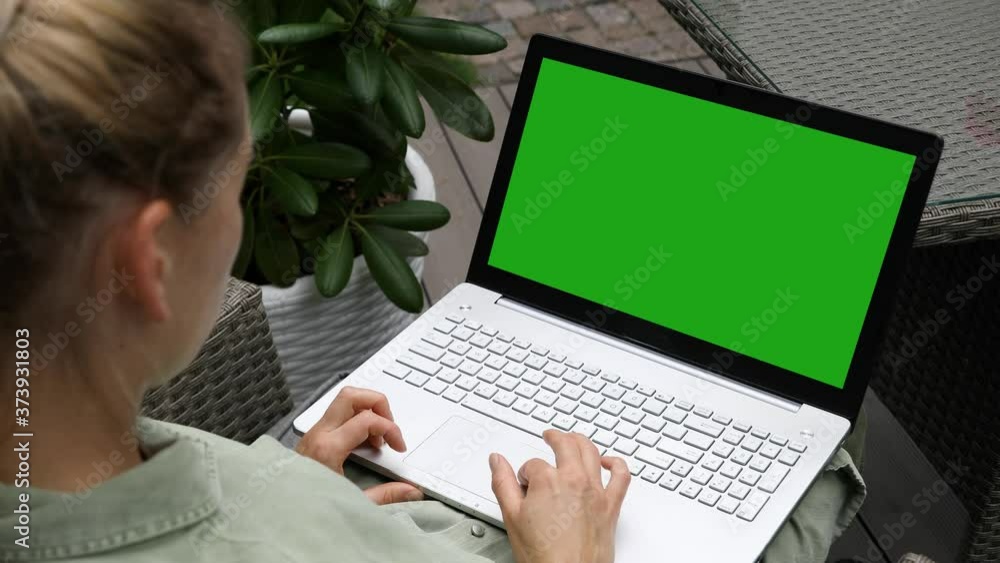 woman using laptop computer on a outdoor terrace, blank green screen ...