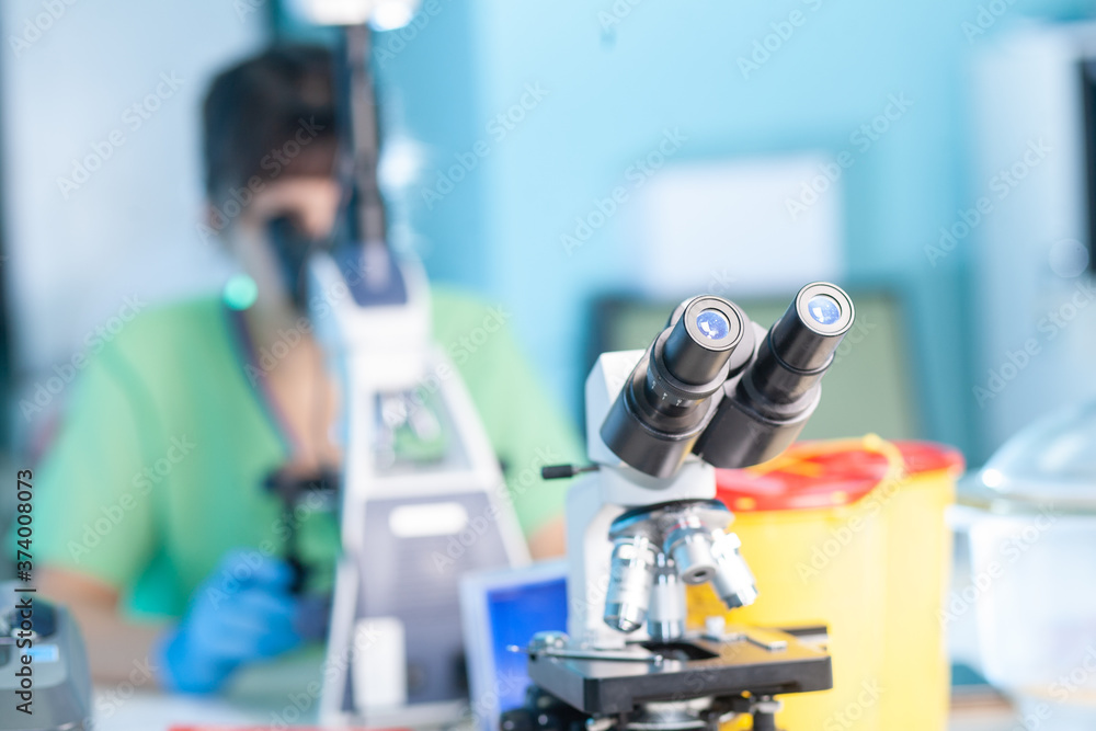 Female professional in uniform. Work with a light microscope in a ...