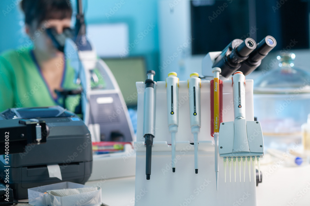 Female professional in uniform. Work with a light microscope in a ...