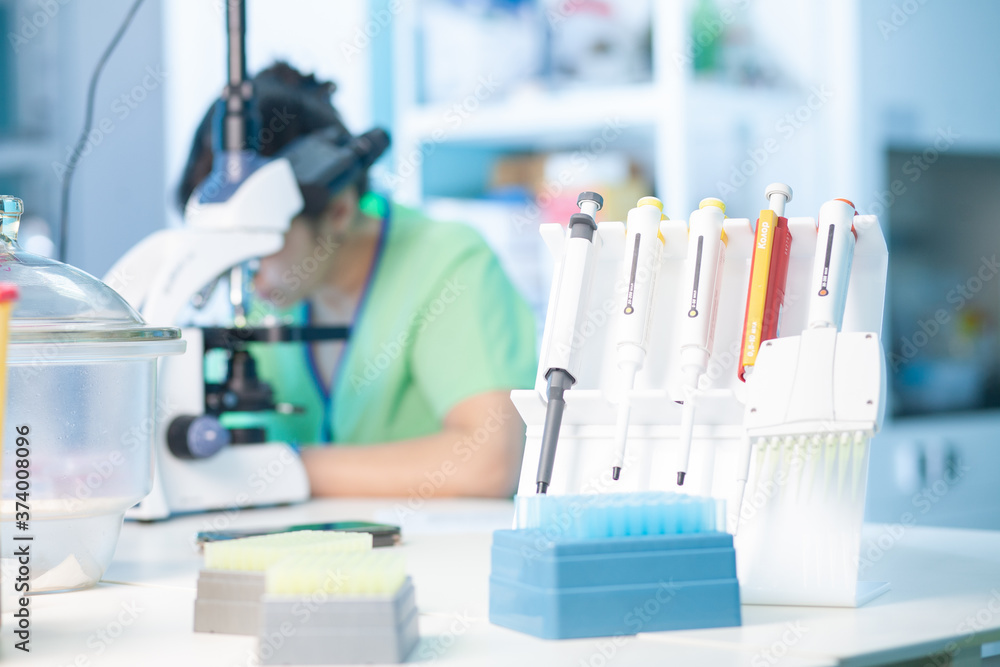 Female professional in uniform. Work with a light microscope in a ...