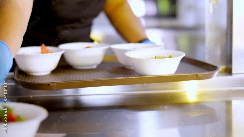 cooking. close-up. waiter, in protective gloves, puts bowls of salads ...