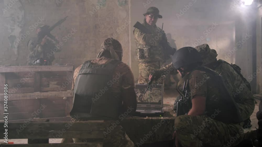 Squad of armed military men in camouflage gathering around army laptop ...