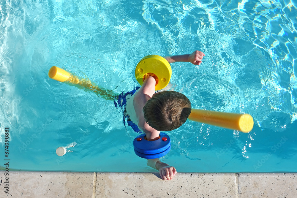 Top view of little boy floating in swimming pool with floats and arm ...