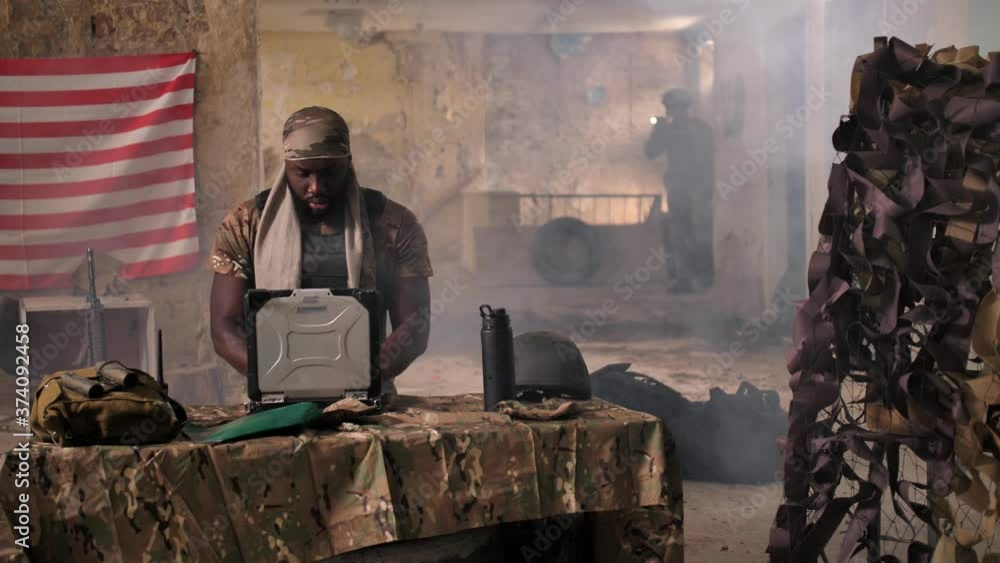 Dark-skinned soldier using army grade laptop for tracking target and ...