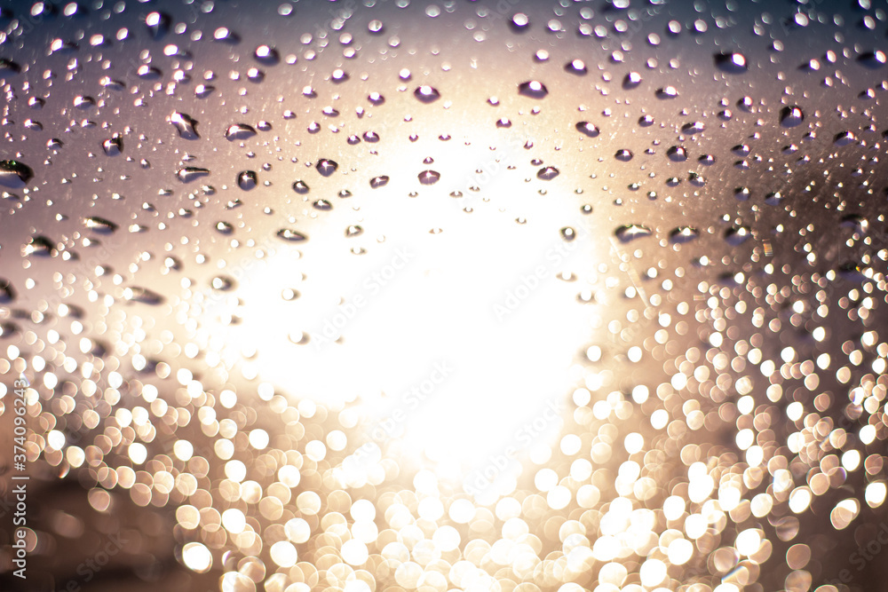 Raindrops on cars window with the yellow sun light in the middle and ...