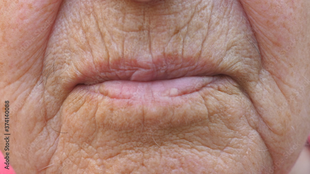 Close up lips of mature grandmother. Mouth of elder grandma sends air ...