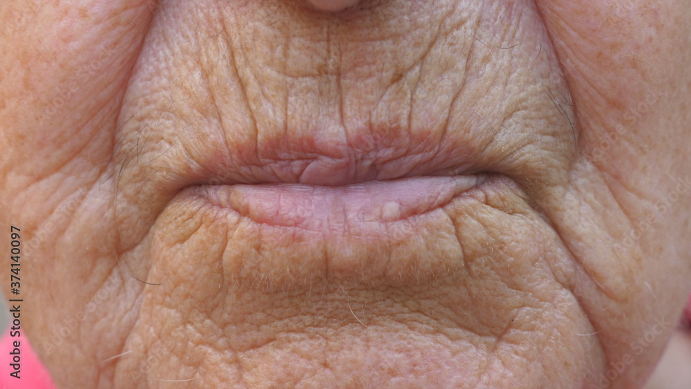 Close up lips of mature grandmother. Mouth of elder grandma sends air ...