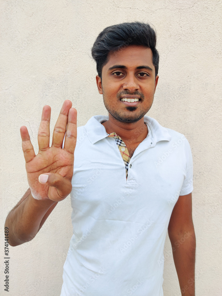 Smiling south indian young man wearing white tshirt pointing up with ...