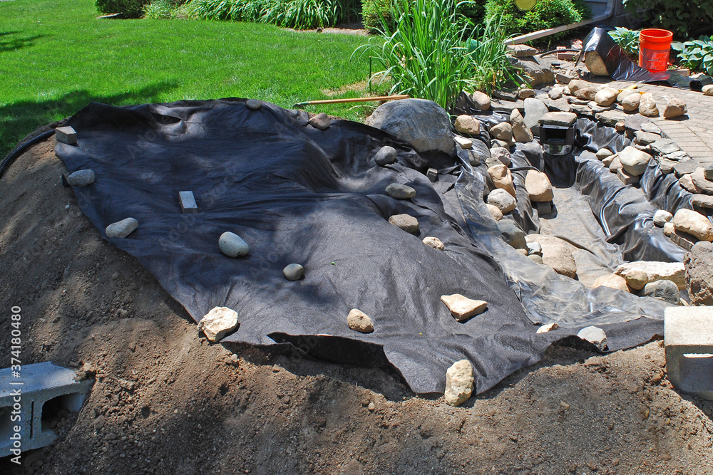 Installation of underlayment for backyard stream and waterfall project ...