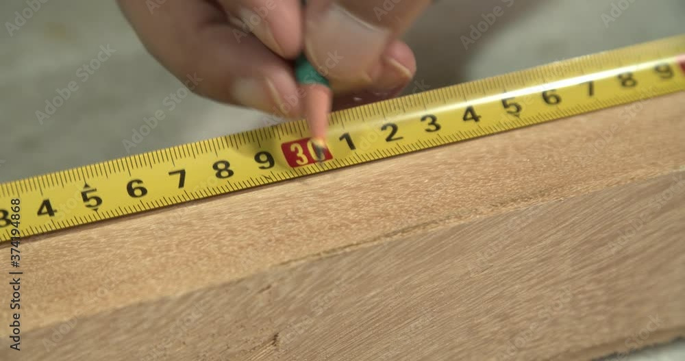 Measuring the size of the wooden board with a tape measure in ...