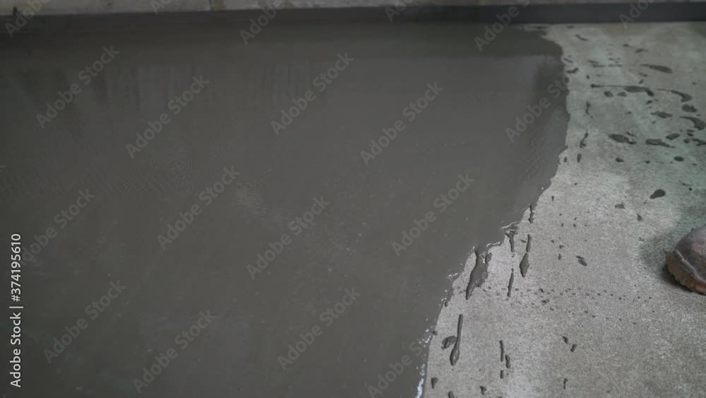 The worker levels the floor with a needle roller. The needle roller is ...