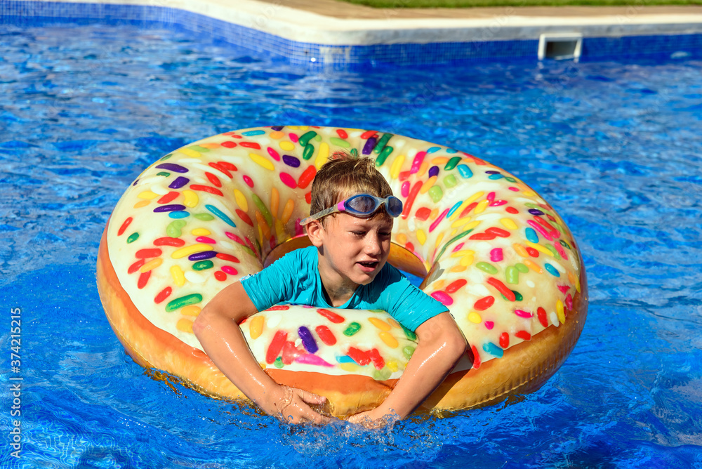 6 year old Boy Bathing In A Transparent Pool Playing With A Large Donut 6-year-old-boy-bathing-in-a-transparent-pool-playing-with-a-large-donut