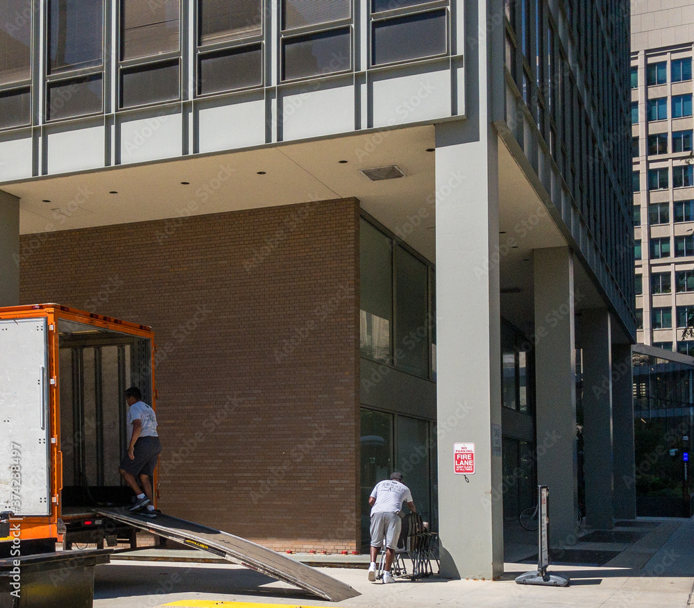 workers with moving truck and ramp rolling chairs into buildings Stock ...