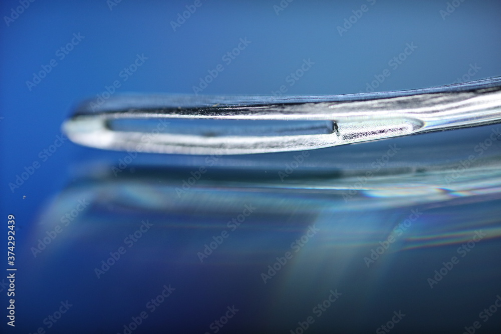 Macro image of the inside of the Eye of a Needle on blue background ...