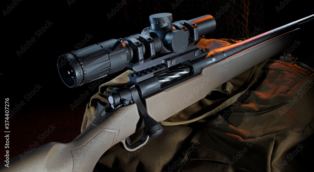 Foto de Bolt action rifle with a scope on a pack with orange rim ...