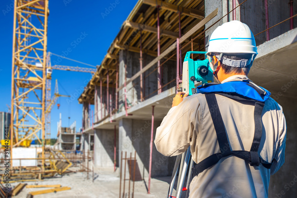 Surveyor next to a building under construction. A man works at a ...