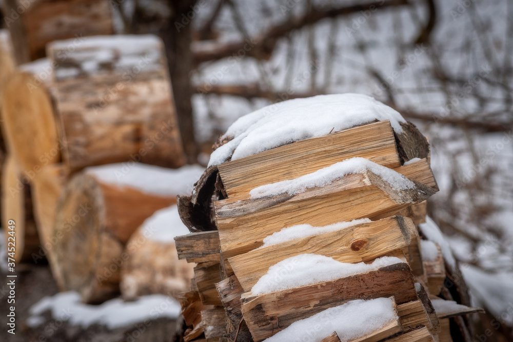 split wood pile, covered with snow, while the cut logs behind fall in ...