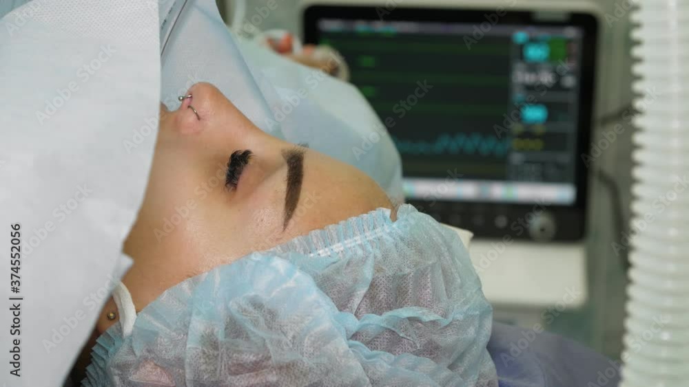 close-up. female patient, in state of anesthesia, lies on operating ...
