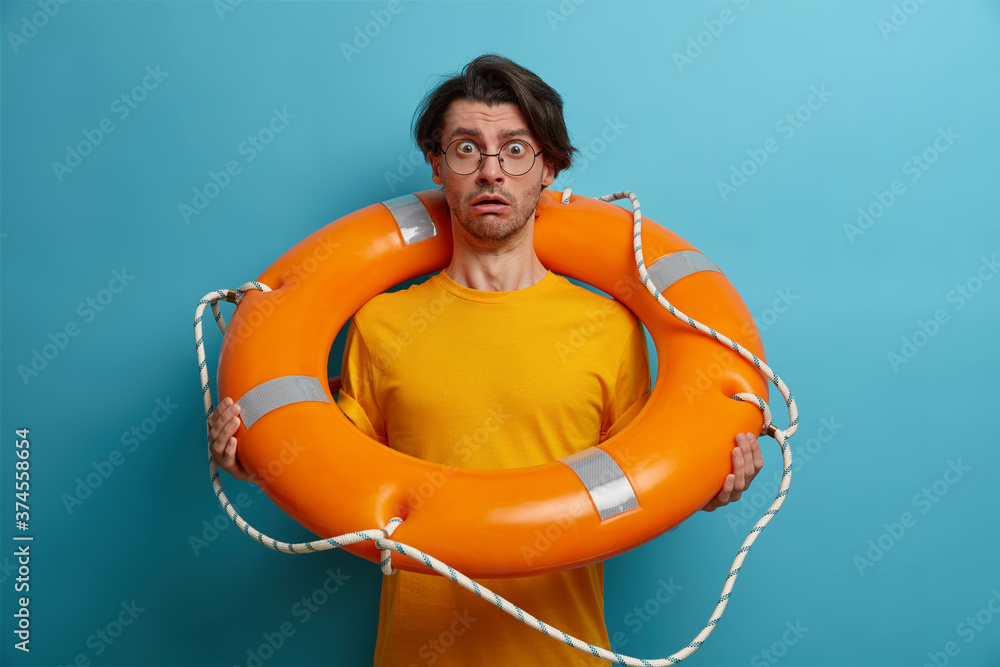 Fearful man afraids of swimming in deep sea, poses with inflated ...