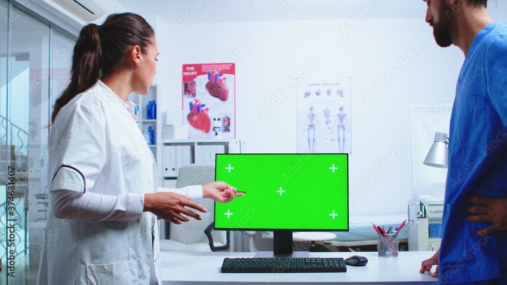 Doctor analysing patient results with assistant on computer with green ...