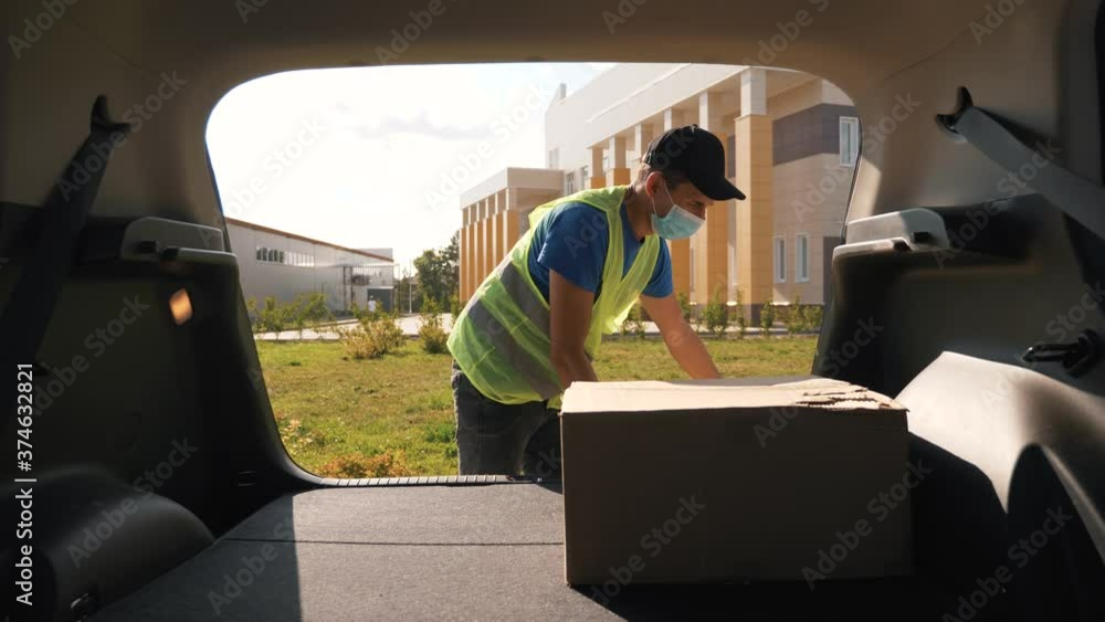 The courier delivers parcels by car. A volunteer man loads cardboard ...