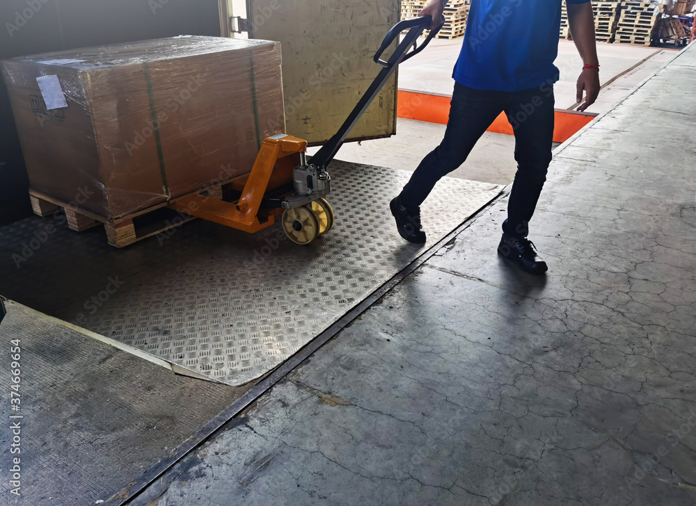 Worker driving forklift loading shipment carton boxes goods on wooden ...