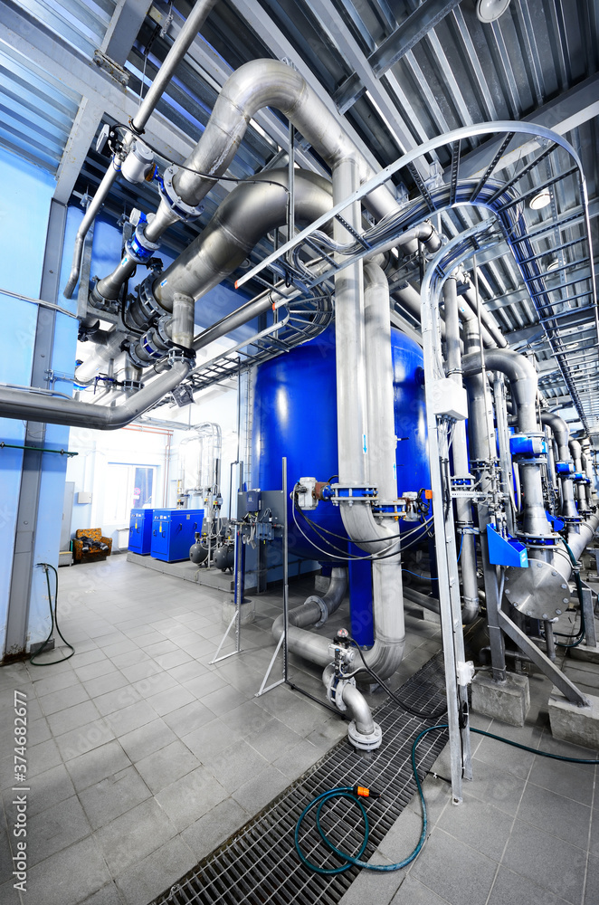 Large blue tanks in a industrial city water treatment boiler room. Wide ...