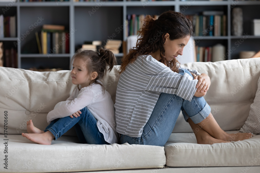 Full length unhappy little preschool baby girl sitting on sofa back to ...