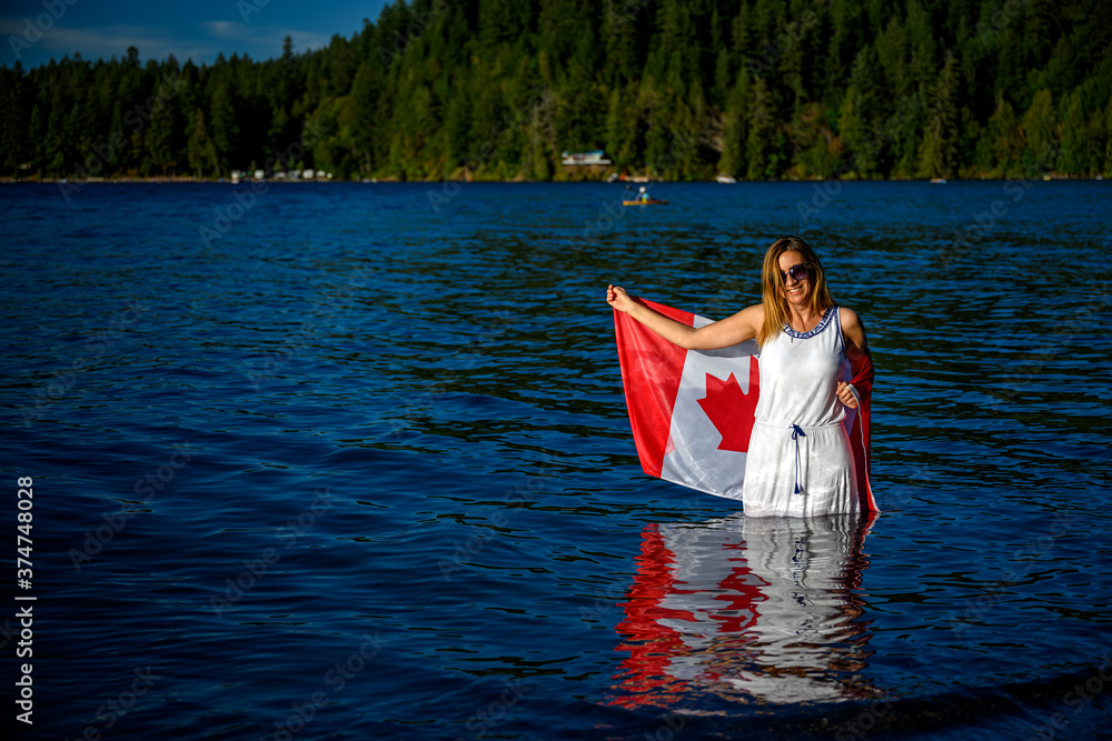 Patriot woman standing in the mazarine color water of the Cultus Lake ...