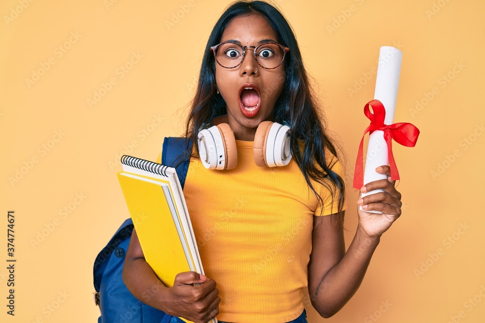 Young indian girl wearing student backpack holding diploma afraid and ...