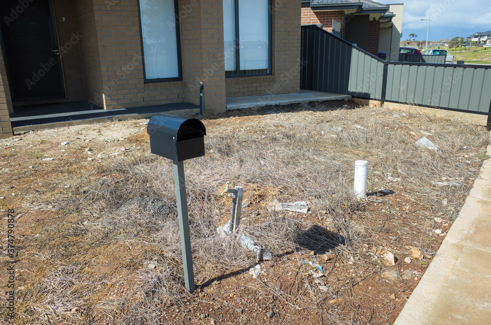 A neglected dry front yard with bare dirt and dead weeds of a ...