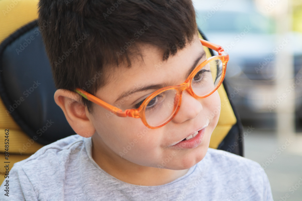 beautiful smiling child's face with orange glasses in a wheelchair ...