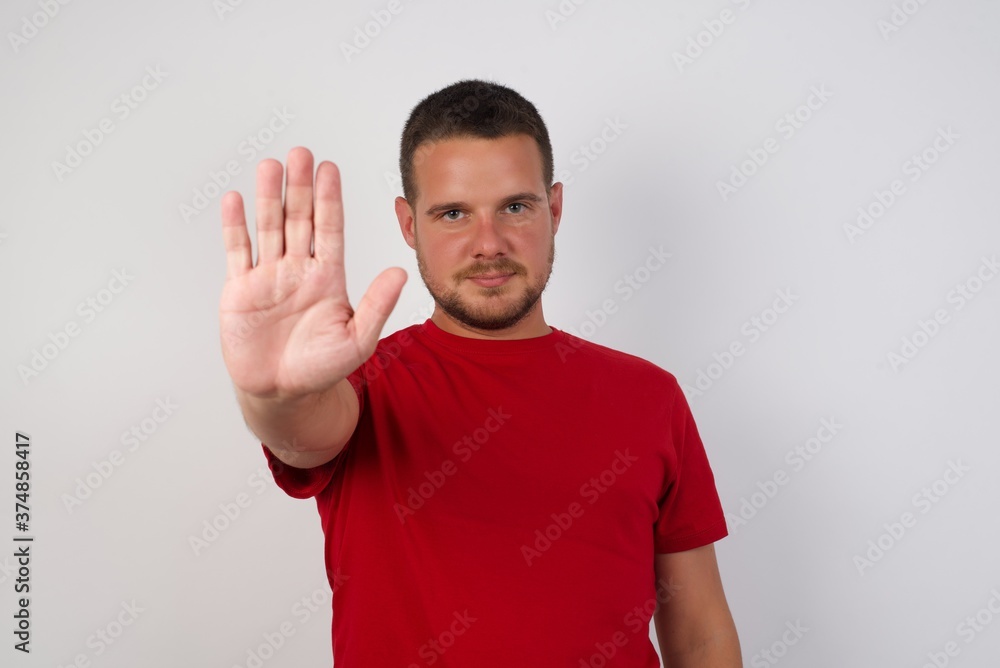Young handsome caucasian man isolated over white background doing stop ...