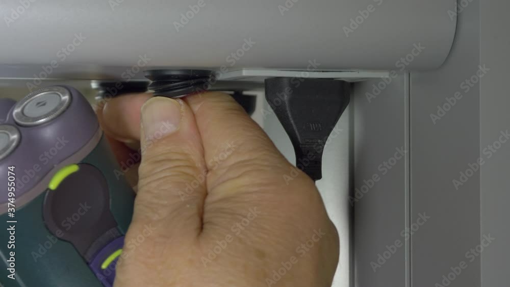 Closeup POV shot of a man’s hand plugging an electric shaver into the ...