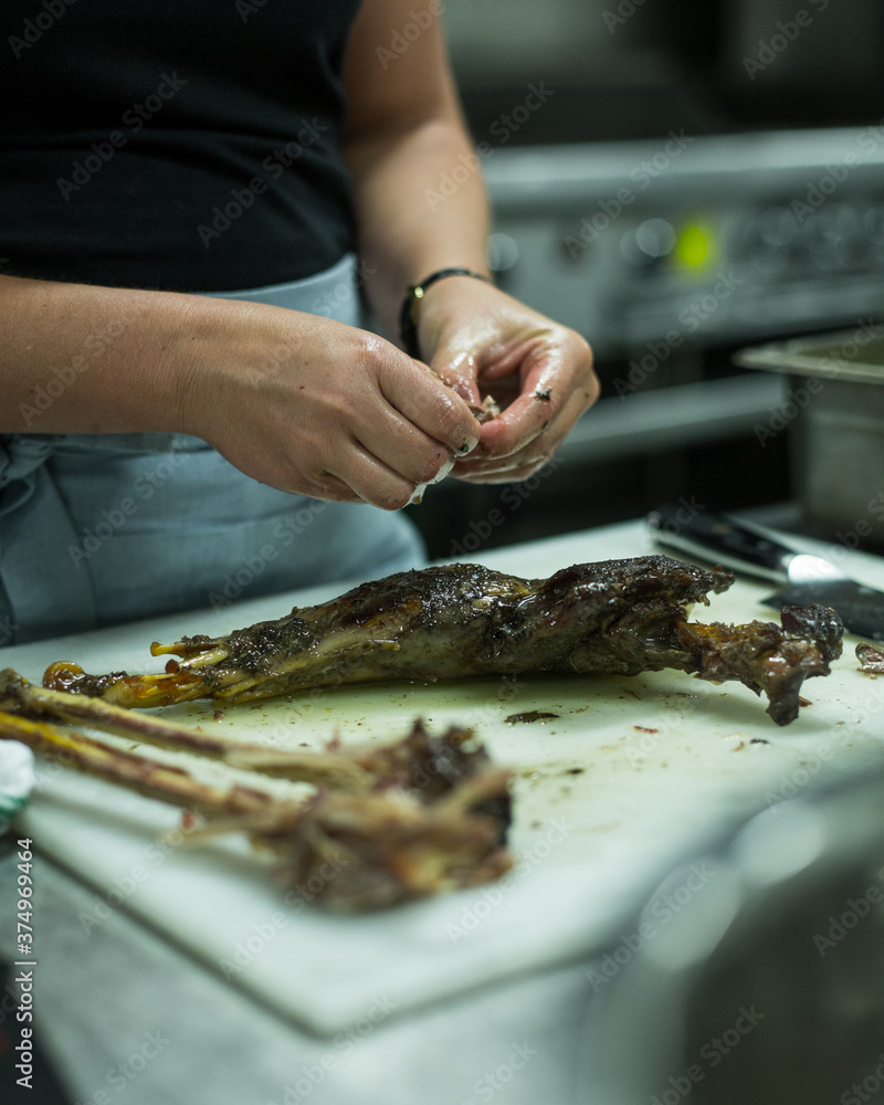 Cook cleaning meat off cooked chicken bones Stock Photo | Adobe Stock